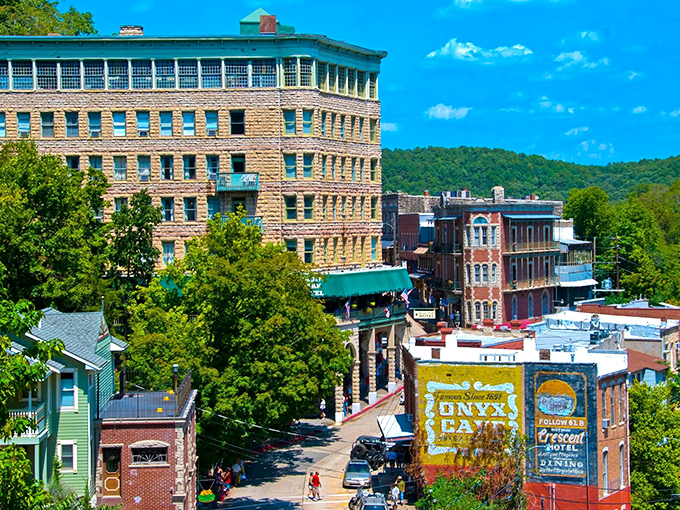 Historic Eureka Springs rises from the Ozark hills like a Victorian dream, with the iconic Basin Park Hotel standing tall among colorful buildings.
