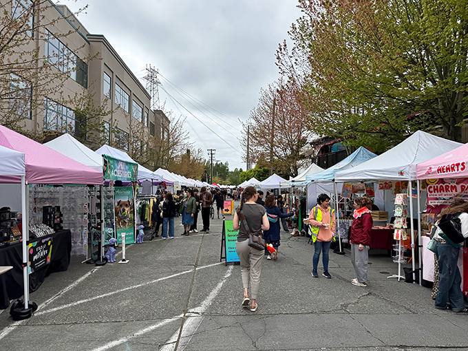 Treasure hunters browse colorful tents at Fremont Sunday Market. Seattle's weekend ritual of discovery unfolds beneath a classic Northwest sky.