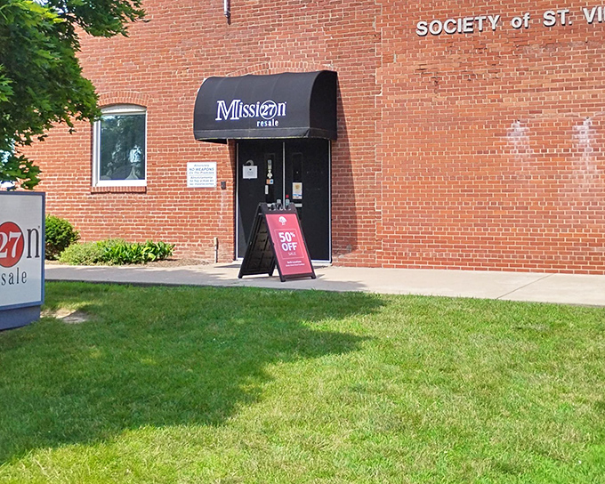 The brick facade of Mission 27 Resale welcomes bargain hunters with a classic awning and promising "50% OFF" sign. Thrift paradise awaits!