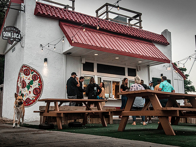 A neighborhood gem beckons! Pizzeria Don Luca's white walls and red roof create the perfect backdrop for picnic table pizza parties under string lights.