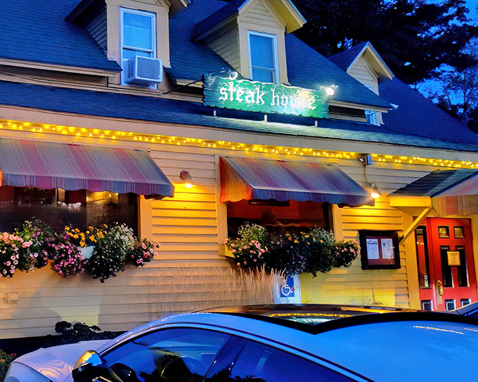 That neon glow in the twilight promises one thing: serious steak and mountain hospitality waiting just beyond those cheerful awnings.