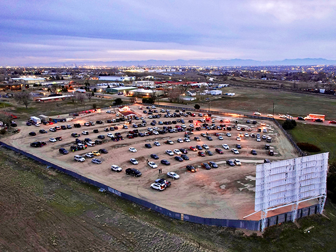 Aerial view of the 88 Drive-In Theatre at dusk, where cars gather like metallic fireflies waiting for movie magic to begin.