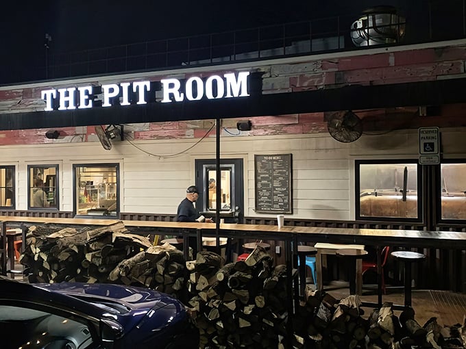 The Pit Room's nighttime glow beckons BBQ lovers like a smoky lighthouse. Stacked firewood out front is their version of a "We Mean Business" sign.