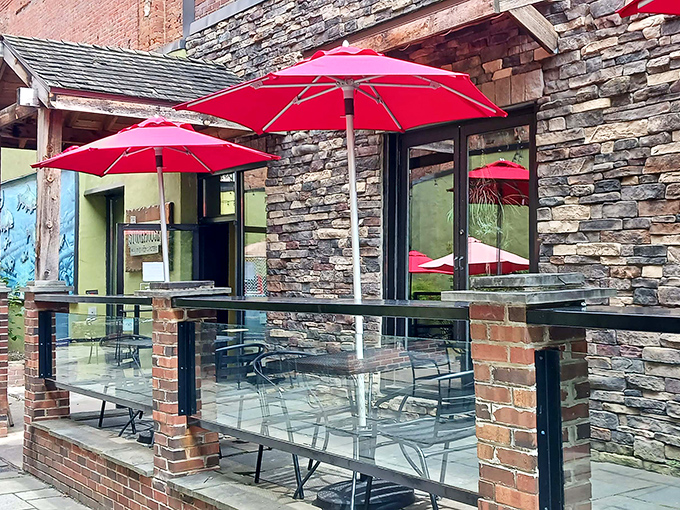 Stone walls and red umbrellas create the perfect backdrop for wood-fired pizza magic happening inside.