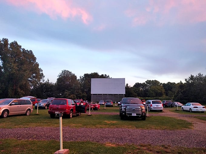 Twilight magic at the drive-in! As the sky blushes pink, vehicles huddle like eager moviegoers, ready for that first flicker of silver screen magic.