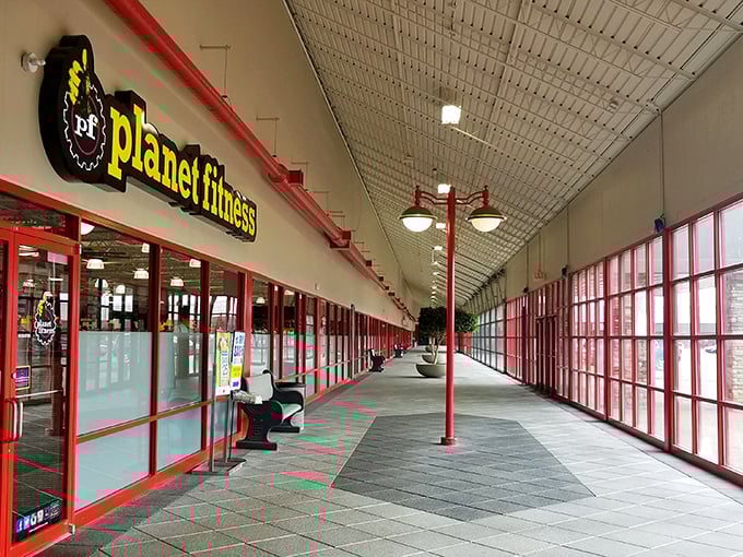 Bright red columns line this spacious indoor walkway at Cedar Creek Mall, where Planet Fitness meets retail therapy in perfect harmony.