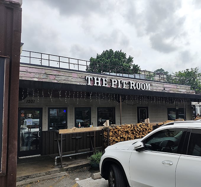 Rustic charm meets serious BBQ at The Pit Room. That woodpile isn't decoration&mdash;it's a promise of good things smoking inside.