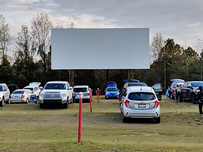 The modern drive-in experience: SUVs and sedans gathered in cinematic communion, proving some traditions deserve their encore performances.