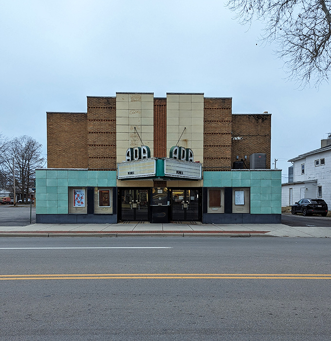The Ada Theatre stands as a teal-trimmed time machine, where movie tickets still cost less than your morning latte.
