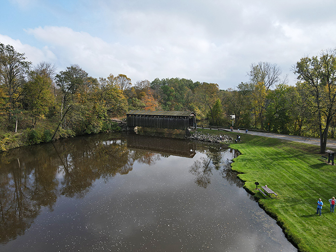 A bird's-eye view reveals the bridge's perfect placement in nature's canvas, where autumn colors frame this historic treasure like a living postcard.
