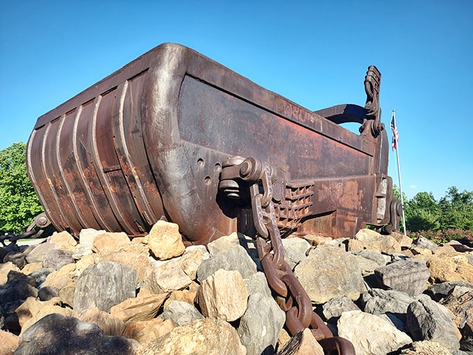 From this angle, the bucket's massive steel frame reveals its battle scars from years of earth-moving duty. Even in retirement, it commands respect.