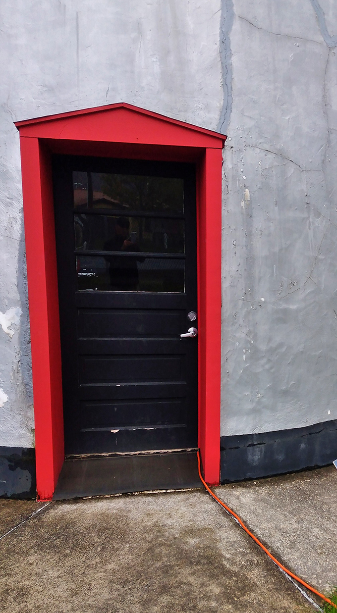 The crimson doorframe invites curious travelers inside. Like Alice's rabbit hole, but with significantly more caffeine potential.