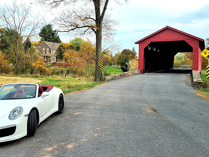 Approaching the bridge feels like driving into a postcard—the vibrant red exterior practically winks at you against autumn's golden palette.