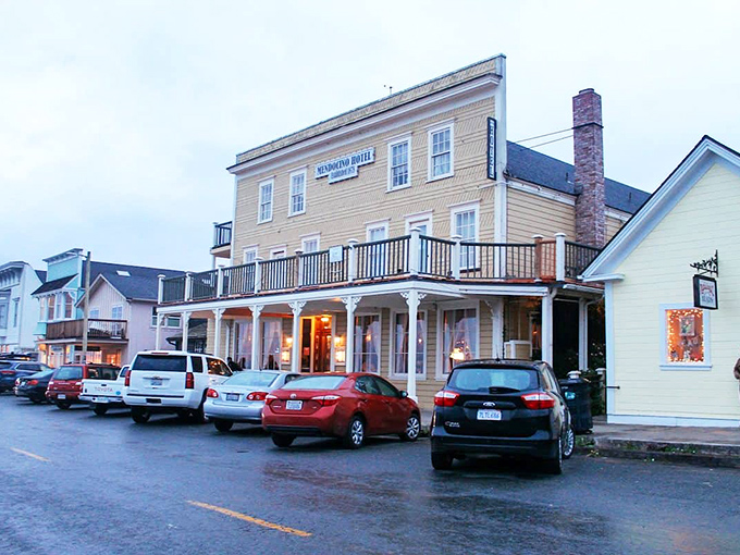 The historic Mendocino Hotel stands sentinel on Main Street, its warm lights promising shelter from coastal fog and stories from another era.