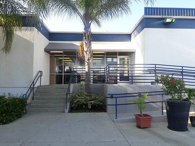 The welcoming entrance, framed by lush greenery and accessibility ramps, invites treasure seekers of all abilities into this secondhand paradise.