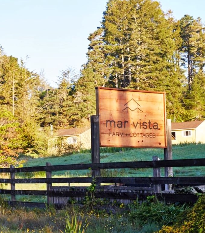 The rustic wooden sign welcomes you to paradise, standing sentinel between civilization and your upcoming digital detox.