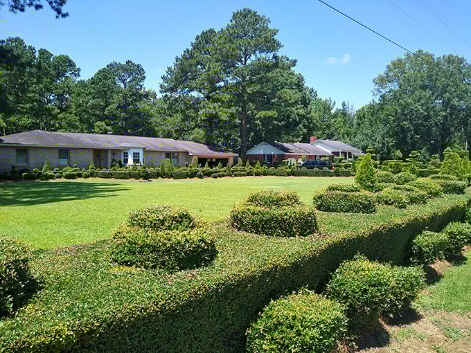 A perfectly manicured landscape where every bush tells a story. The contrast between the modest brick home and these fantastical green creations couldn't be more delightful.