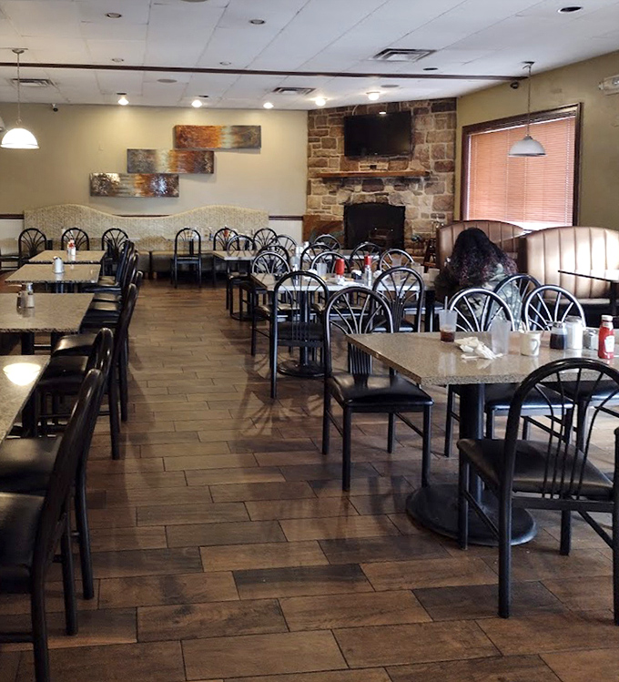 Warm wood tones, comfortable seating, and that stone fireplace create the perfect backdrop for morning conversations and coffee refills.