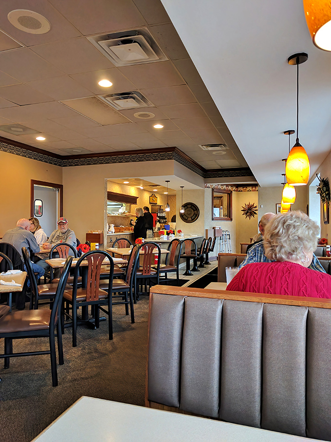 Inside, pendant lighting casts a warm glow over comfortable booths where regulars exchange morning pleasantries and newcomers become instant friends.