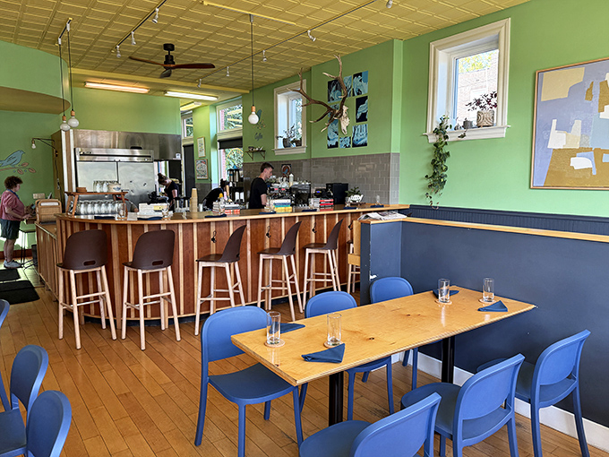 Mint green walls and blue chairs create a fresh, inviting atmosphere where breakfast dreams come true. The pressed tin ceiling adds vintage charm.