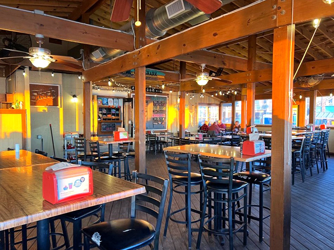 Exposed wooden beams, string lights, and simple furnishings create that rare atmosphere where both flip-flops and business casual feel equally at home.