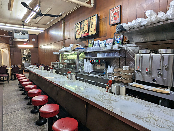 The counter stretches like a runway of culinary possibilities, those red vinyl stools having supported generations of Detroiters seeking honest food at honest prices.