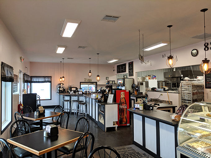 Morning light streams through windows, illuminating a caf&eacute; space where pendant lights hang like promises of coffee and comfort.