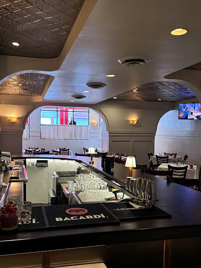 The elegant bar area, with its ornate tin ceiling and warm lighting, offers the perfect perch for people-watching while sipping a perfectly crafted Negroni.