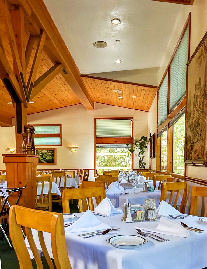 Wooden beams and warm lighting transform this dining room into a French countryside retreat where white tablecloths signal: something special is about to happen.