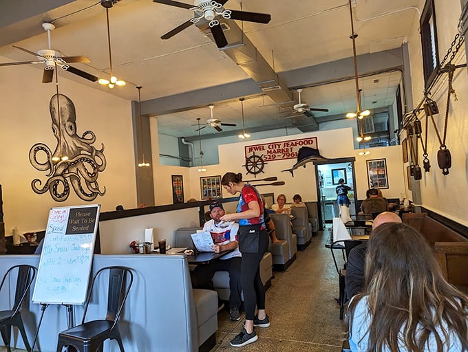 Nautical charm meets cozy comfort inside, where that magnificent octopus mural watches over diners like a benevolent sea guardian. The ceiling fans almost create a maritime breeze.