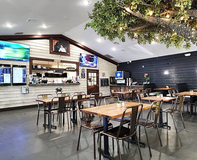 Inside, the contrast of white shiplap and dark wood creates a modern-rustic vibe, while that overhead tree installation adds a touch of whimsy to mealtime.