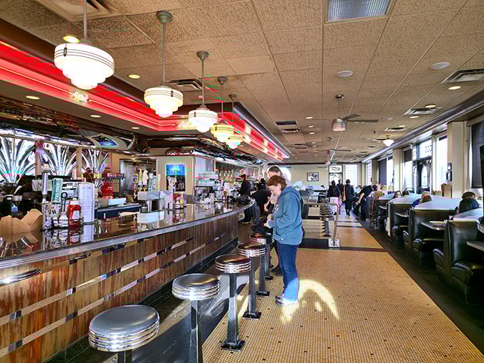 Inside, the counter stretches like a runway for comfort food, where chrome stools await hungry patrons and conversations flow as freely as the coffee.