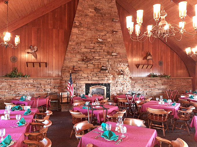 Stone fireplace, wooden beams, and pink tablecloths create the quintessential supper club atmosphere. Comfort wrapped in rustic elegance.