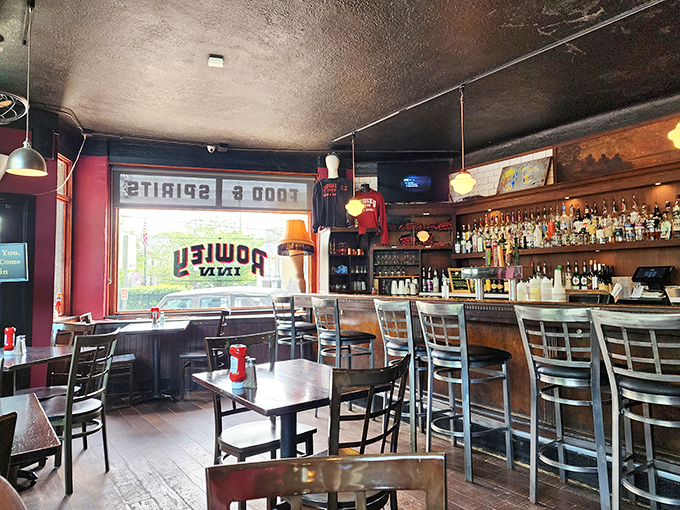 Inside, the warm glow of pendant lights illuminates a classic tavern where conversations flow as freely as the drinks behind that well-stocked bar.
