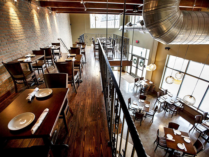 A two-story dining experience where exposed brick meets warm wood, creating that rare atmosphere that's both sophisticated and "hey, take your shoes off" comfortable.