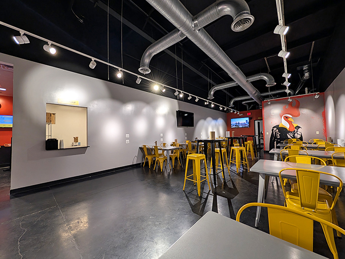 Industrial-chic meets Southern hospitality with exposed ductwork hovering above cheerful yellow chairs—the calm before the spicy storm.
