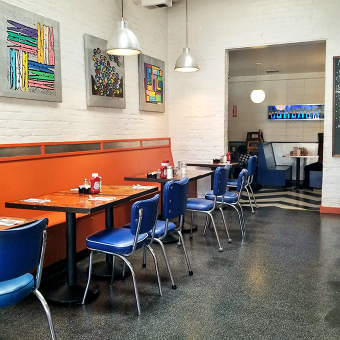 Orange booths and blue chairs create a retro symphony that feels both nostalgic and perfectly current. This isn't decoration&mdash;it's time travel with better coffee.