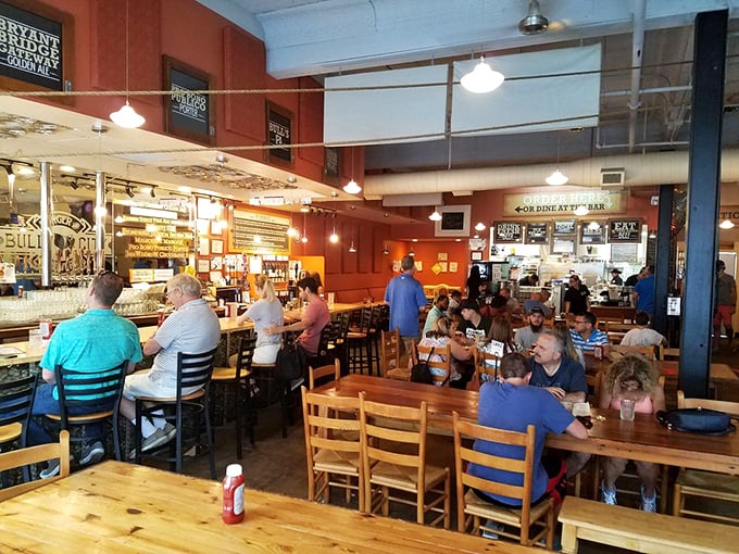 Inside Bull City, warm orange walls and wooden communal tables create that rare atmosphere where strangers become friends over shared plates and pint glasses.