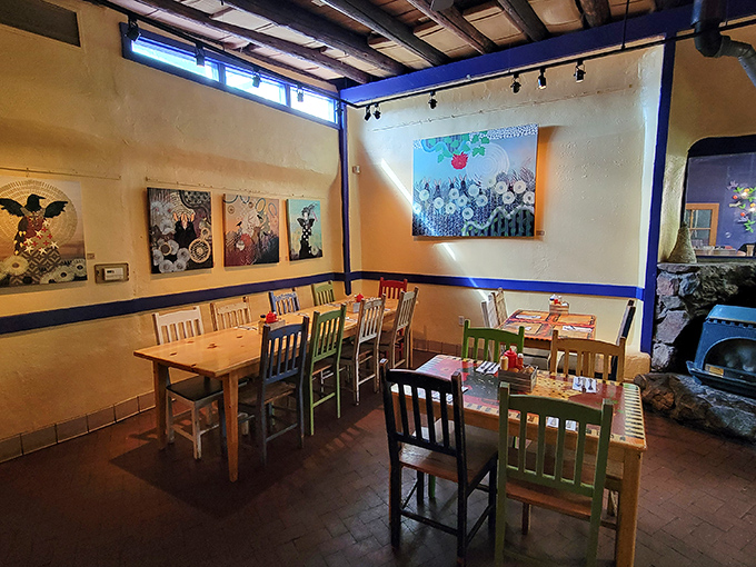 Colorful chairs gather around wooden tables beneath local artwork, creating dining spaces that feel like your most artistic friend's kitchen.