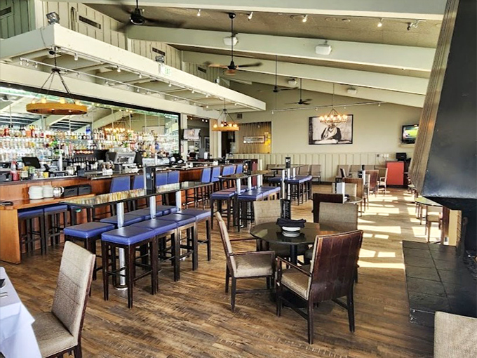 Sunlight streams through the windows, turning the bar area into a cathedral of casual dining where conversations flow as freely as the cocktails.