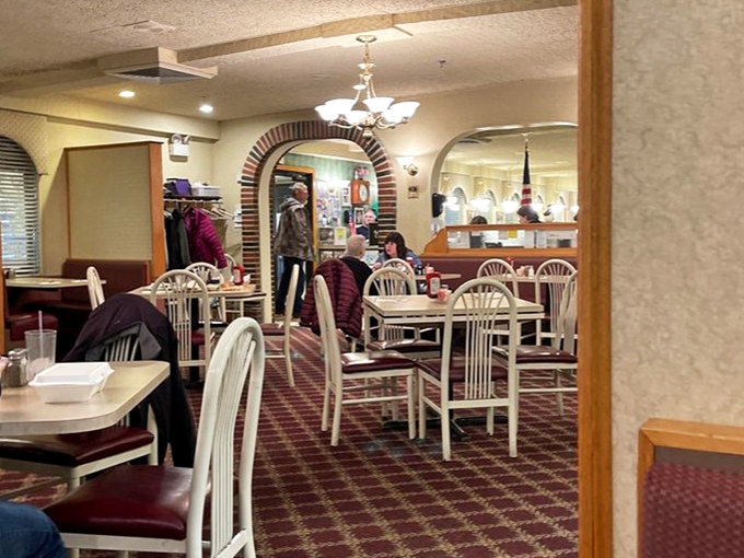 Classic white chairs and patterned carpet create that unmistakable diner atmosphere where conversations flow as freely as the coffee. Comfort never goes out of style.