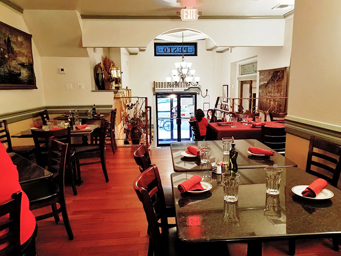 Red napkins pop against dark wood tables in this intimate dining room, where every meal feels like Sunday dinner at nonna's house.