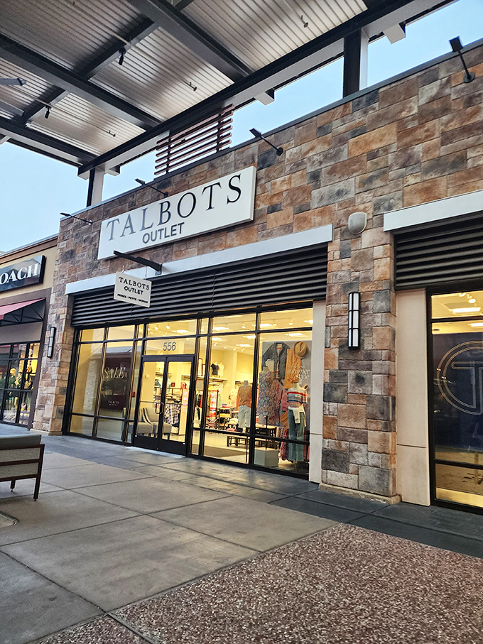 Talbots' stone facade gleams in the evening light, promising classic styles without the classic prices. Window shopping becomes actual shopping here.