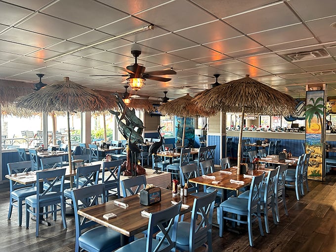 Thatched umbrellas hover over blue chairs like personal clouds, creating little islands of tropical ambiance where seafood dreams come true.