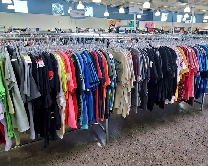 A rainbow of possibilities hangs in perfect formation. Each shirt has a story, each color a potential new chapter in your wardrobe saga.