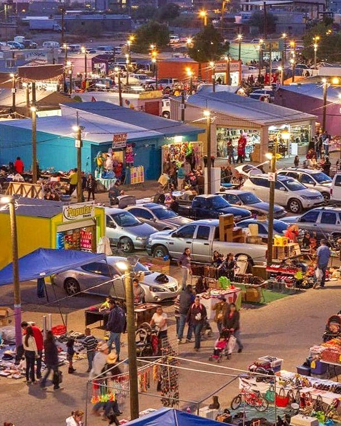 As twilight falls, the swap meet transforms into a glowing village of commerce. From above, the maze of stalls resembles a miniature city of possibilities.