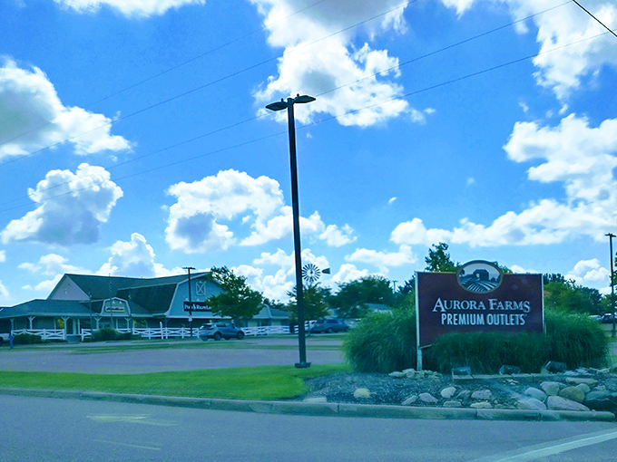 Blue skies and bargains await at Aurora Farms Premium Outlets, where the entrance sign promises retail adventures ahead.