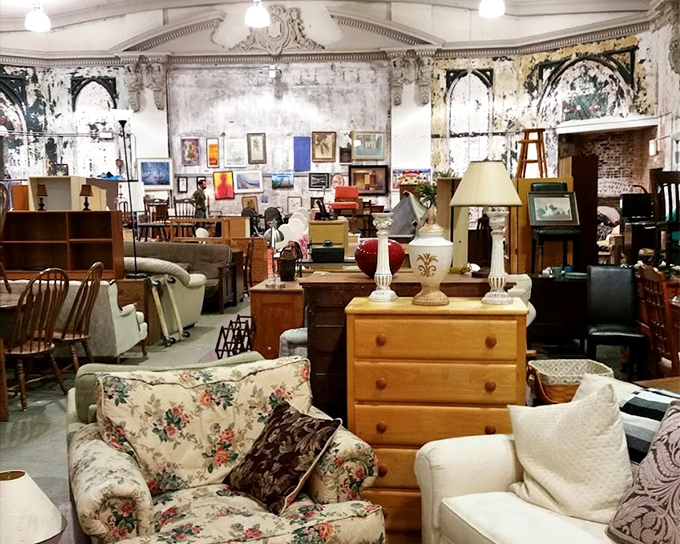 A floral armchair sits patiently among wooden dressers and lamps, waiting for someone to recognize its potential as the perfect reading nook.