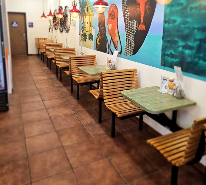 Simple wooden booths line the wall beneath vibrant sea-themed murals. No white tablecloths needed when the food does all the talking.