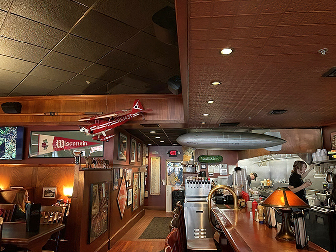 Model airplanes and Wisconsin memorabilia hang from the ceiling, creating a museum of nostalgia where burgers are the main exhibit.